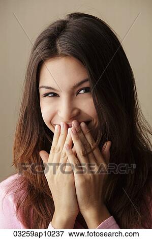 Picture of young woman laughing while covering her mouth with her hands ...