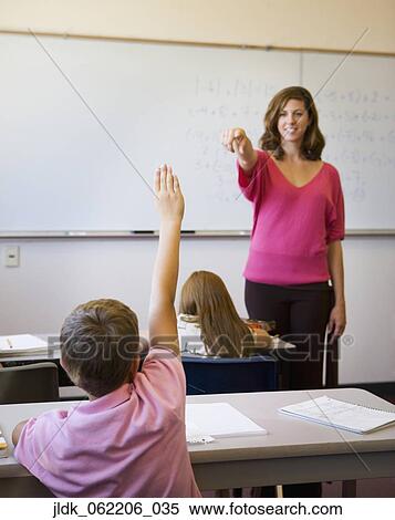 Stock Image of Female teacher calling on student in classroom jldk ...