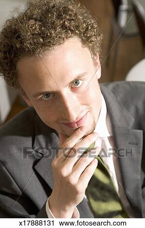 Young man resting hand on chin, smiling, portrait, close-up Stock Image ...