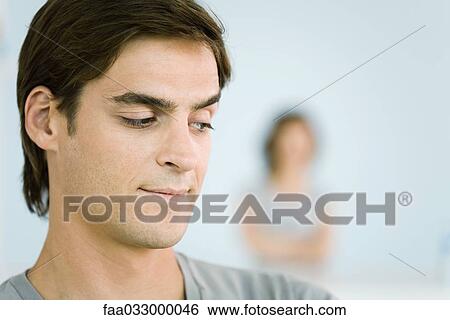 Man making sideways glance over shoulder, woman with arms folded in ...