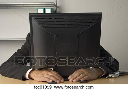 Stock Photograph of Businessman hiding behind computer monitor foc01059 ...