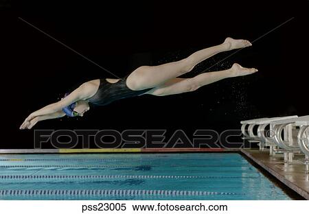 Stock Image of Female swimmer diving off starting block mid-air ...