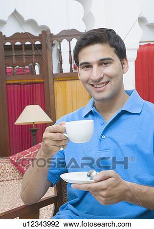 Portrait of a young man holding a tea cup and a saucer Stock Image ...